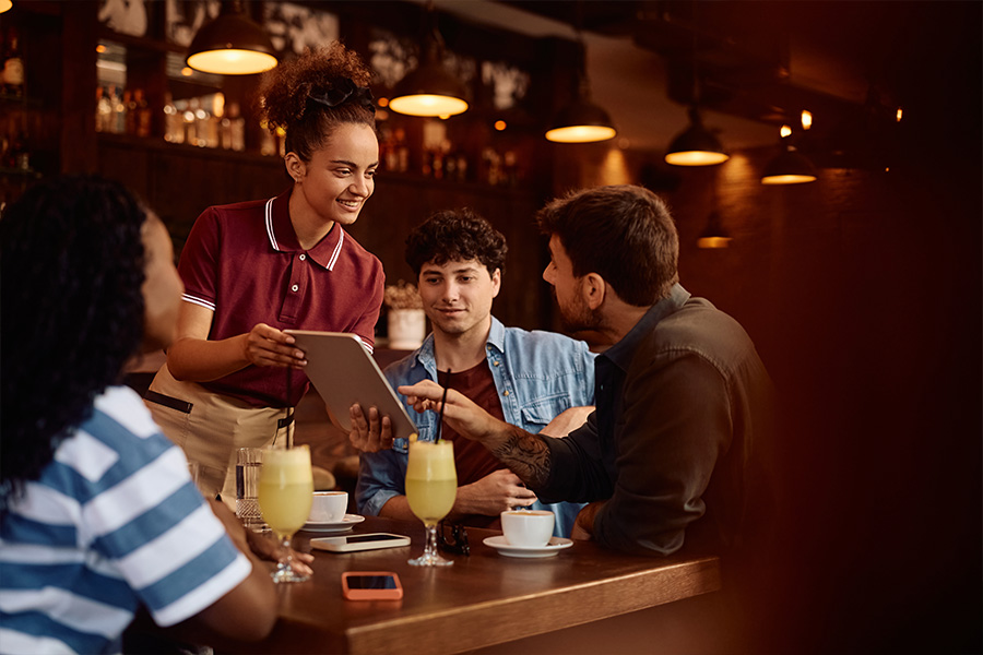 happy-waitress-showing-menu-on-touchpad-to-group-o-2024-12-13-22-24-29 ...